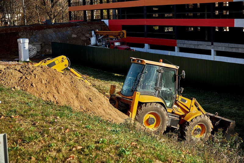 Yellow Backhoe Loader Digs the Ground Under the Road during Road ...