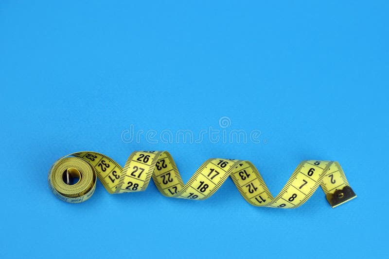 Yellow Measuring Tape is Twisted in a Spiral on a Blue Background. Copy ...