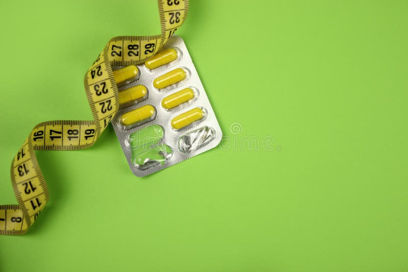 Yellow Measuring Tape Wrapped in a Spiral and Tablets on a Green ...