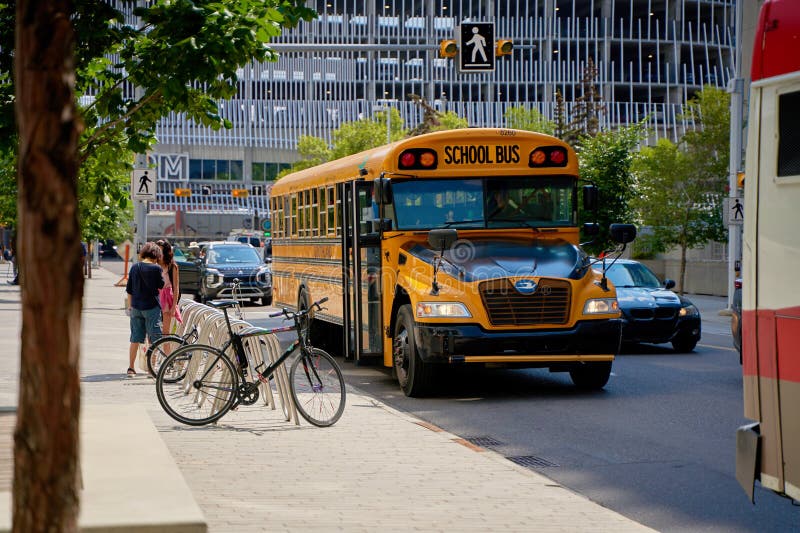 A Yellow Old School Bus Drives through the Modern City of Calgary ...