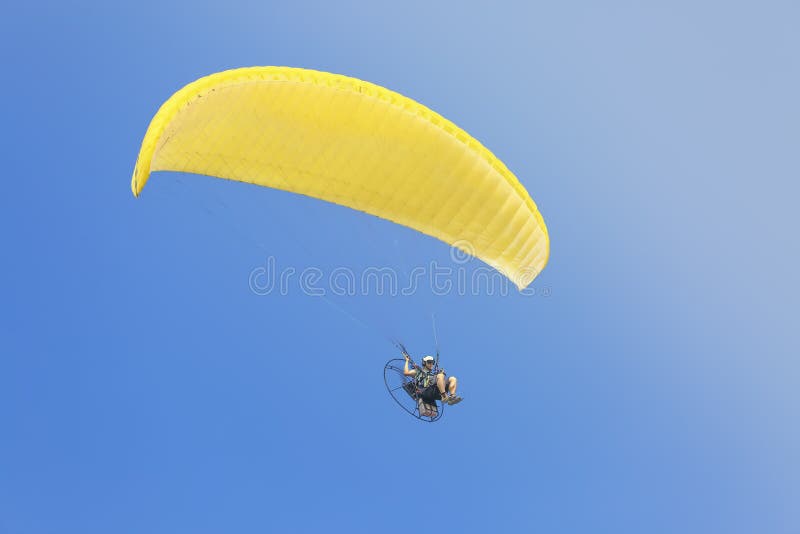 A Yellow Paraglider with a Paramotor, Soaring in the Rays of the ...