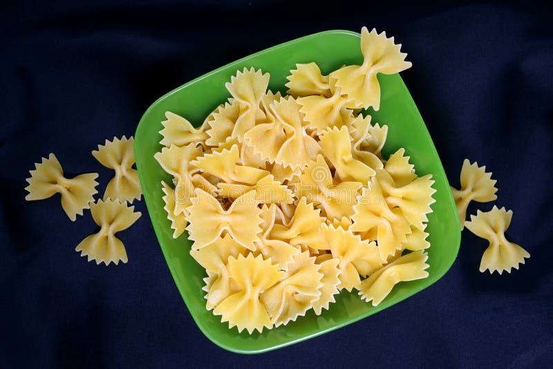 Yellow Pasta in the Shape of a Bow in a Green Bowl on a Blue Background ...