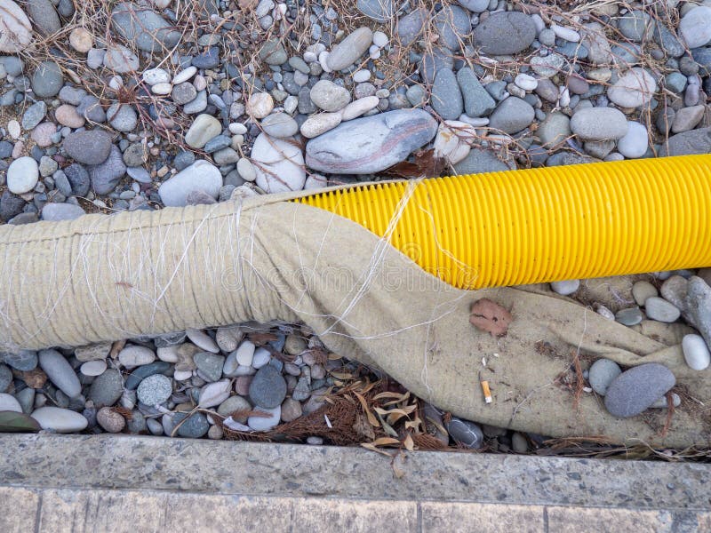 Yellow Pipe on Stone Pebbles. Technical Communications on the Beach ...