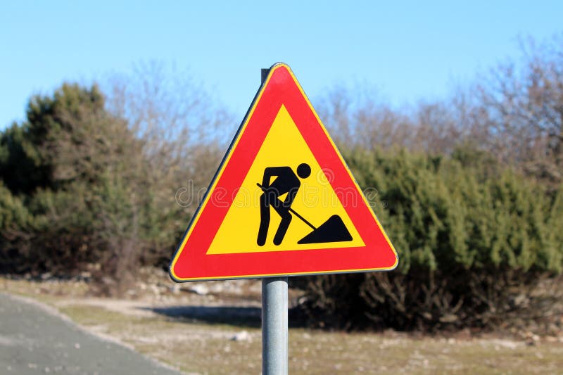 Yellow and Red Triangular Roadwork Warning Sign by Roadside Vegetation ...