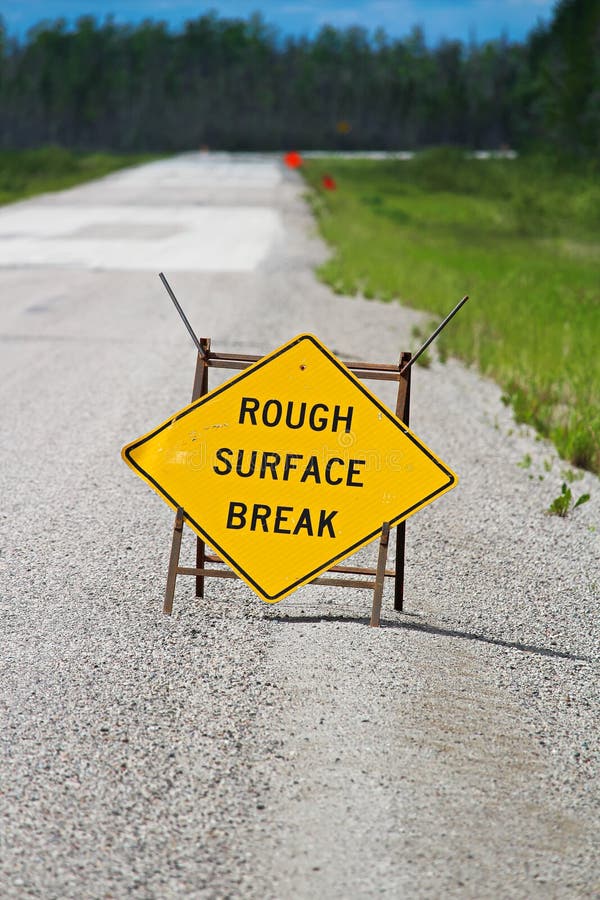 A Yellow Rough Surface Break Sign with a Road Blurring into the ...