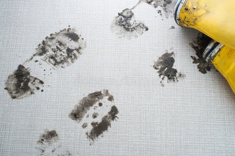 Yellow Rubber Boots Create Distinct Muddy Footprints on a Light-colored ...