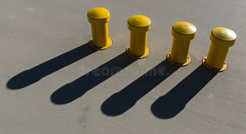 Yellow Safety Posts Casting Long Shadows on a Concrete Surface in ...