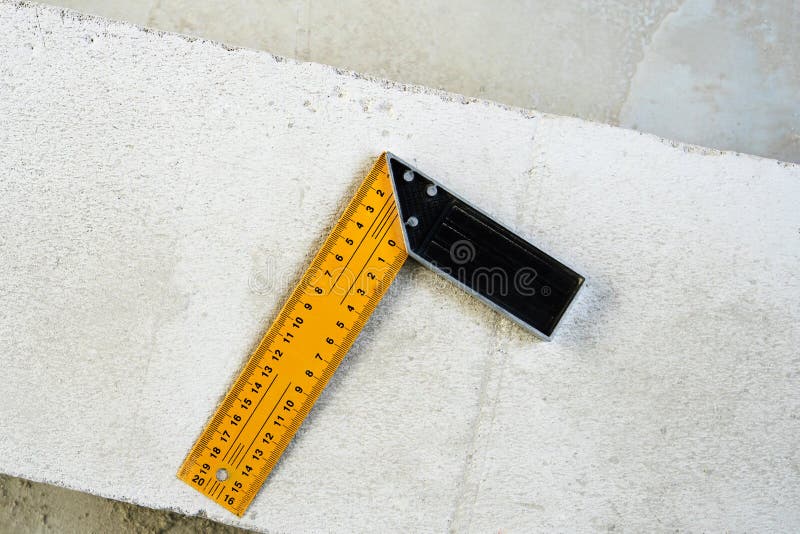 A Yellow Square Ruler Lies on a White Brick. Precise Construction Tools ...