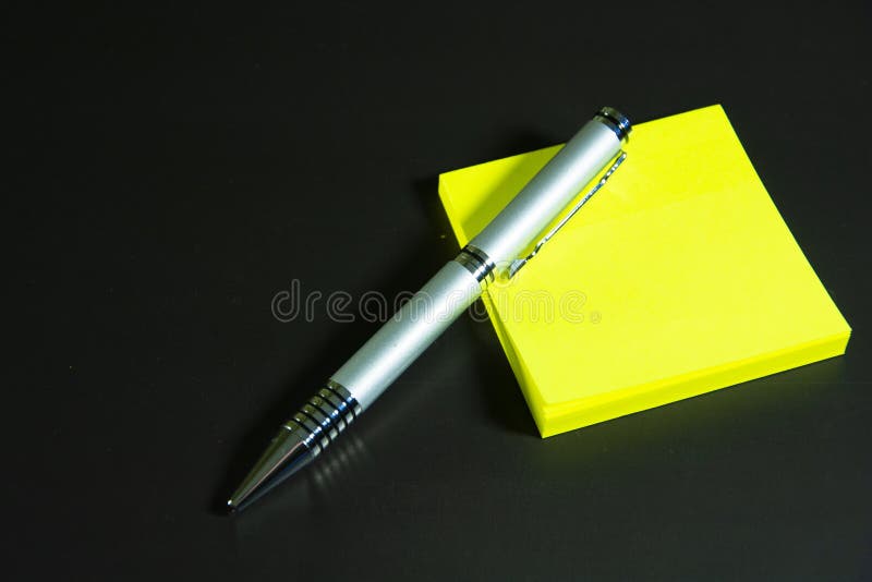 Yellow Stickers and a Silver Ballpoint Pen Lie on a Black Matte Surface ...