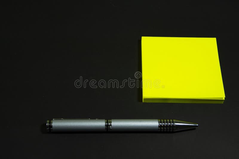 Yellow Stickers and a Silver Ballpoint Pen Lie on a Matte Black Surface ...