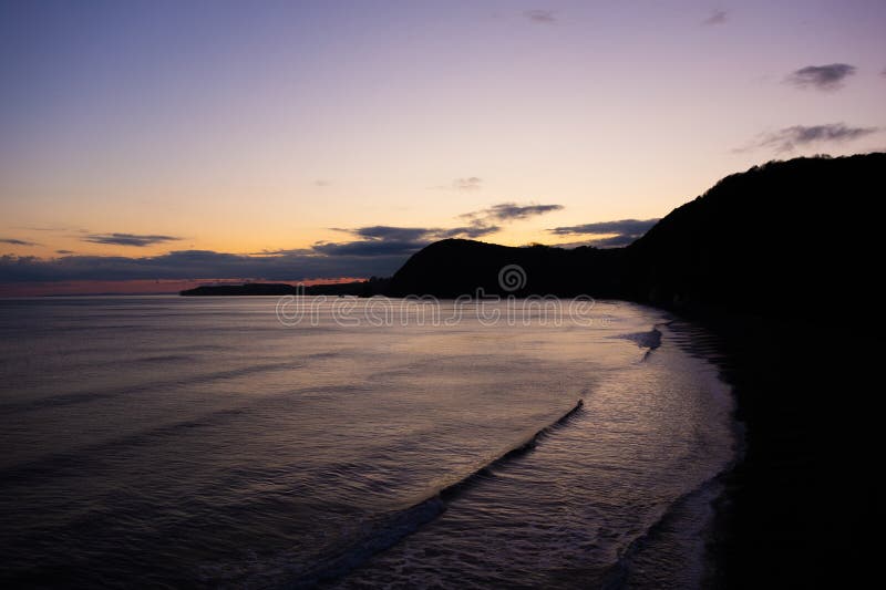 Yellow Sunset Behind the Cliffs with a Curving Beach Stock Photo ...