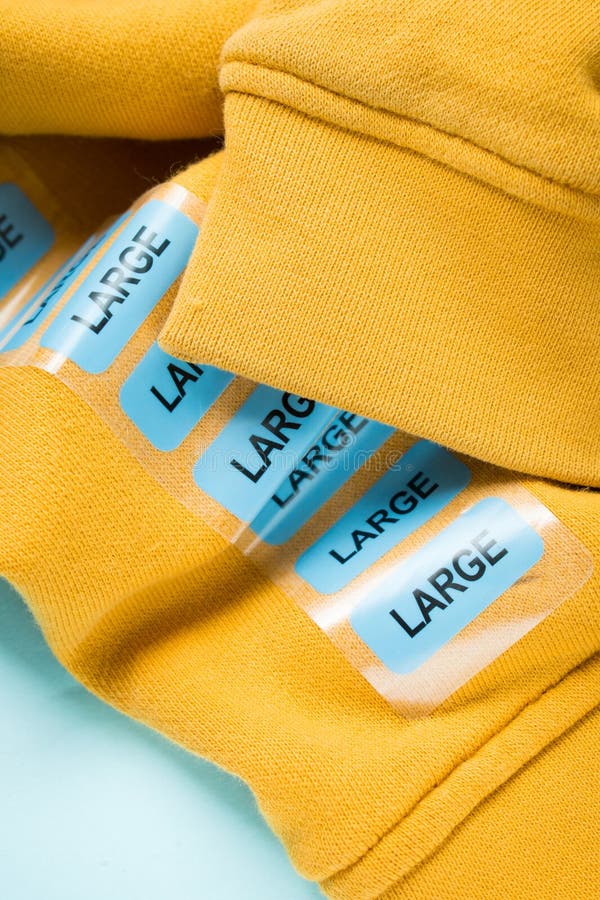 Yellow Sweater Sitting on Top of a Table Covered in Labels Stock Photo ...