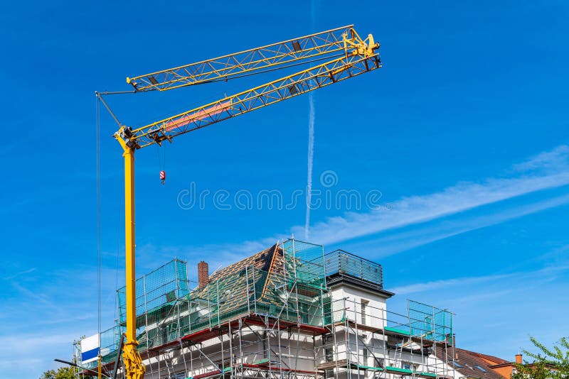 Yellow Tower Crane Over a House Under Construction Surrounded by ...