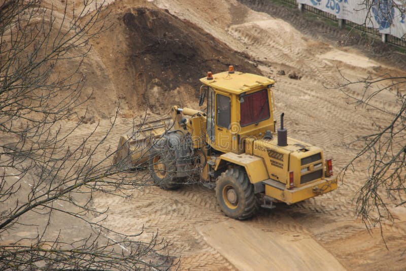 Yellow Tractor Collecting Digging in the Construction Site. Building ...
