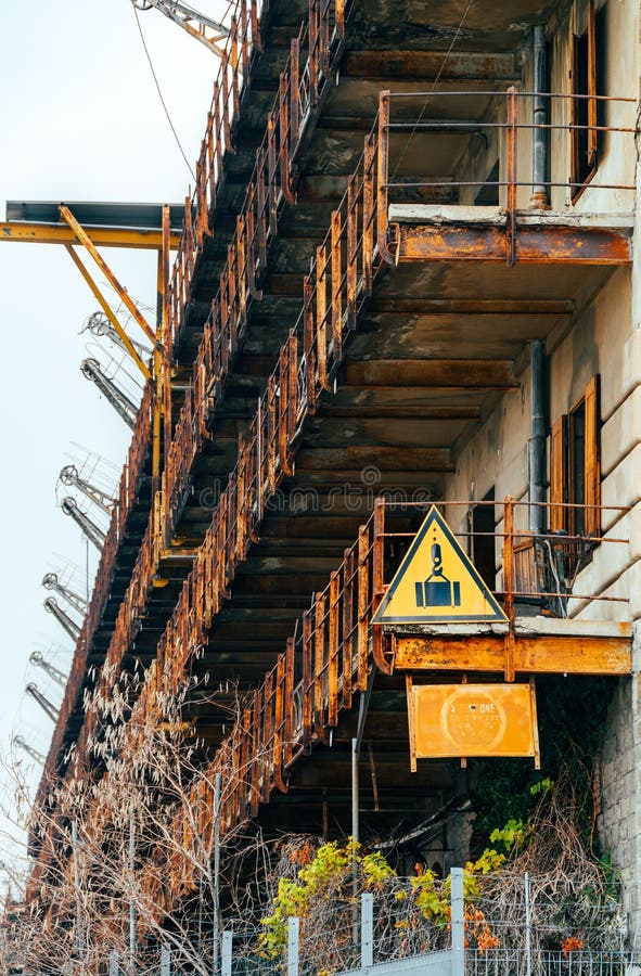 A Yellow Triangular Sign Hangs on the Dilapidated Rusty Balconies of an ...