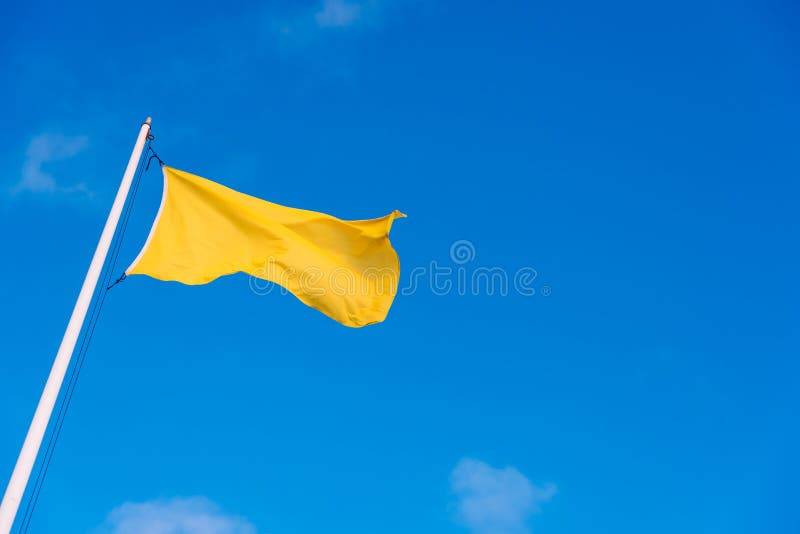 Yellow Warning Flag on a Beach Against the Blue Sky Background Stock ...