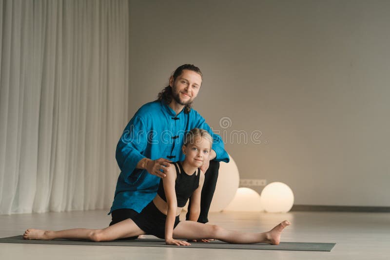 A Yoga Instructor in Training Helps a Child To Do Exercises in the Gym ...