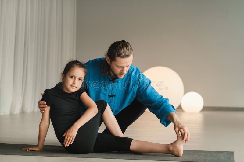 A Yoga Instructor in Training Helps a Child To Do Exercises in the Gym ...