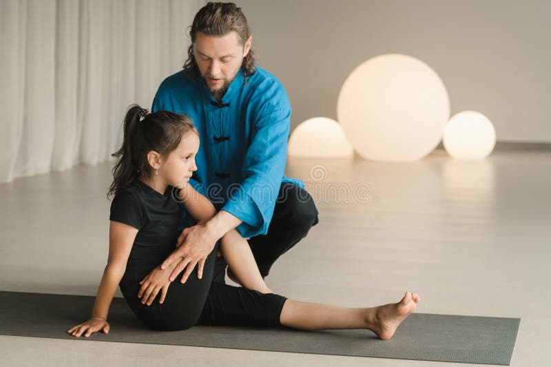 A Yoga Instructor in Training Helps a Child To Do Exercises in the Gym ...