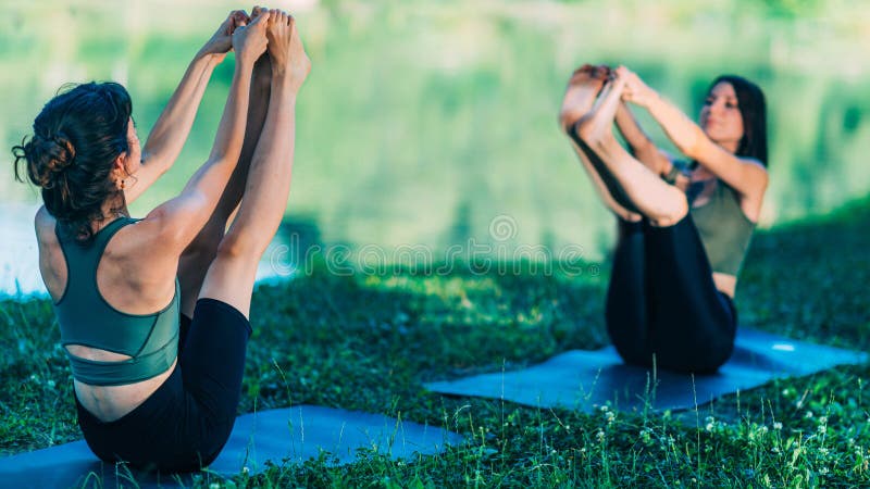 Women Doing Yoga by the Water. Instructor Helping Woman To Do Headstand ...