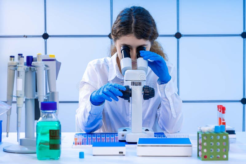 Young Adult Female Student Working with a Microscope Examining ...
