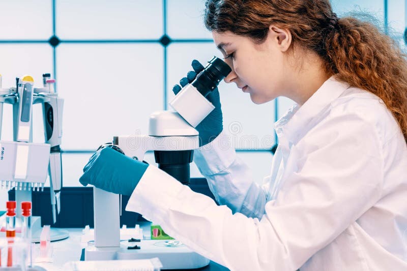 Young Adult Female Student Working with a Microscope Examining ...