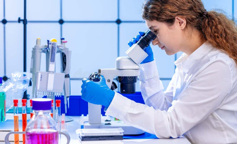 Young Adult Female Student Working with a Microscope Examining ...