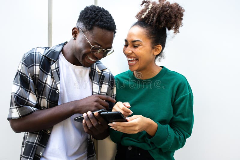 Young African American Couple Laughing Together Using Smart Phones