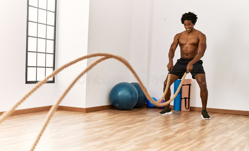 Young African American Man Training Using Battle Rope at Gym Stock ...