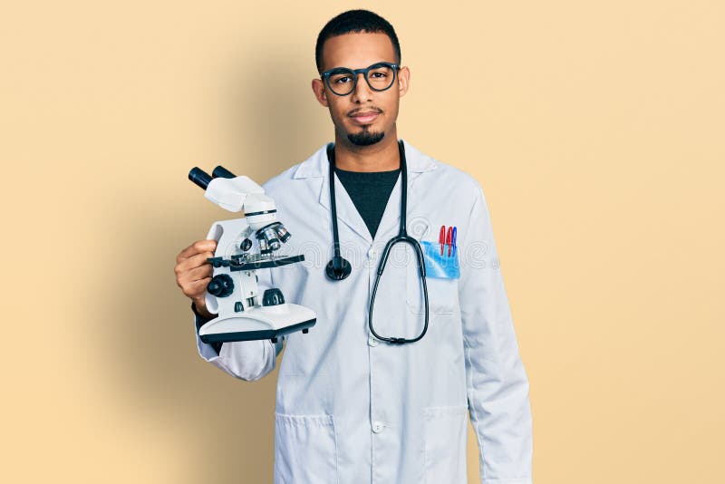 Young African American Man Wearing Scientist Uniform Holding Microscope ...