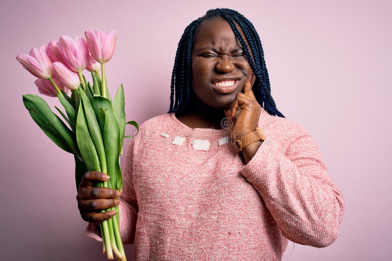 Young African American Plus Size Woman With Braids Holding Bouquet Of
