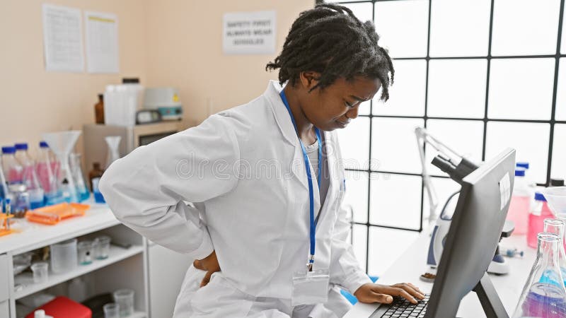 A Young African American Woman with Dreadlocks, Feeling Back Pain while ...