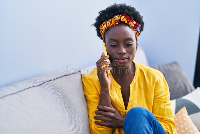 Young African American Woman Talking On The Smartphone Sitting On Sofa