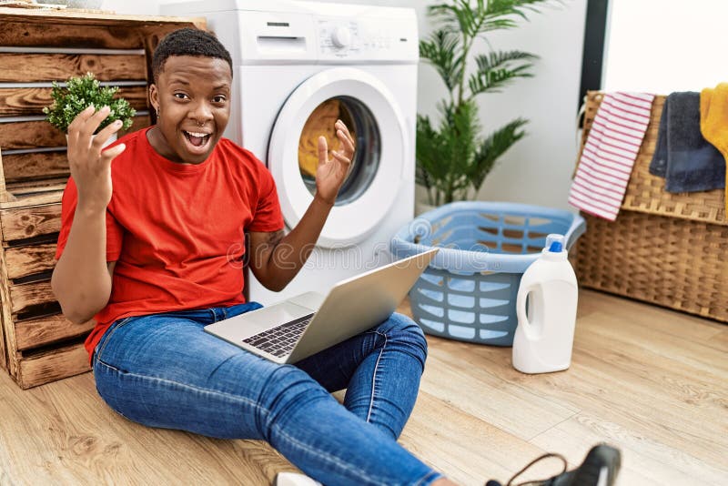 Young African Man Doing Laundry and Using Computer Celebrating Crazy ...