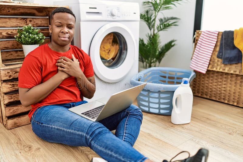 Young African Man Doing Laundry and Using Computer Smiling with Hands ...