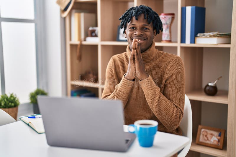 Young African Man with Dreadlocks Working Using Computer Laptop Praying ...