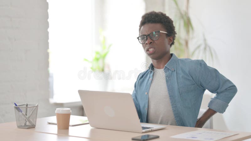 Young African Man Having Back Pain while Using Laptop in Office Stock ...