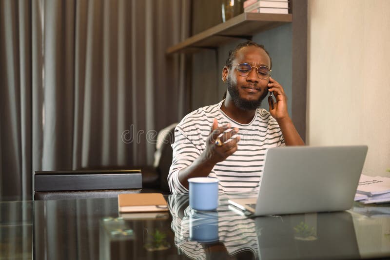 Young African Man Having Serious Phone Conversation and Working with ...