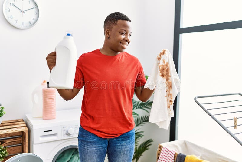 Young African Man Holding Dirty Tshirt and Detergent at Laundry Room ...