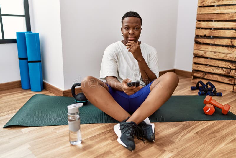 Young African Man Sitting on Training Mat at the Gym Using Smartphone ...