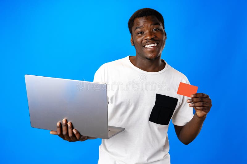 Young African Man Standing and Using Laptop Computer Over Blue ...