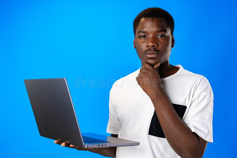 Young African Man Standing and Using Laptop Computer Over Blue ...
