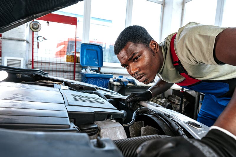 Young African Man Working Under the Hood of Car Fixing Engine in Auto ...