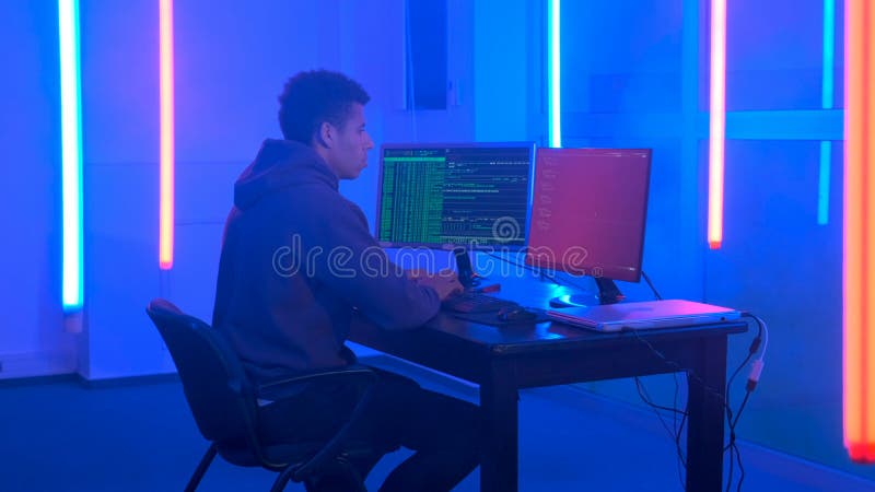 Young African Man Writing Hacker Programs in Dark Room with Neon Lights ...