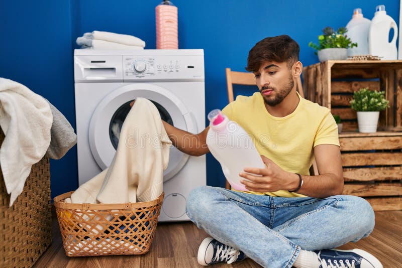 Young Arab Man Looking Detergent Bottle Sitting on Floor at Laundry ...