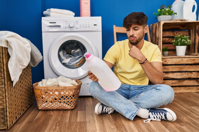 Young Arab Man Looking Detergent Bottle Sitting on Floor at Laundry ...