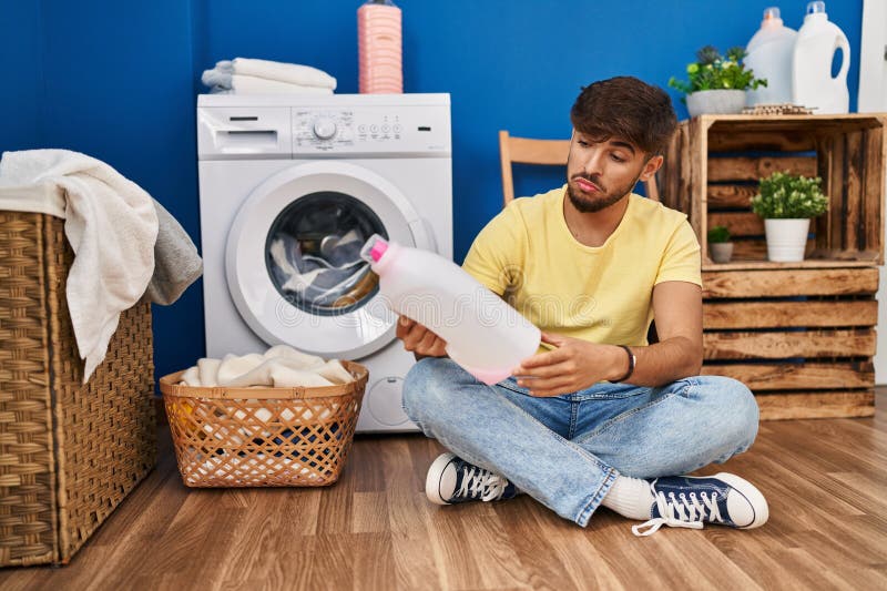 Young Arab Man Looking Detergent Bottle Sitting on Floor at Laundry ...
