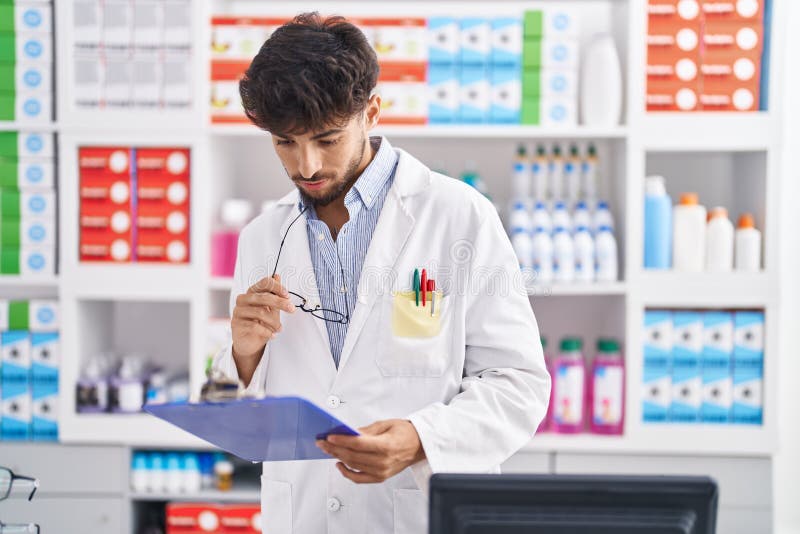 Young Arab Man Pharmacist Reading Document at Pharmacy Stock Image ...