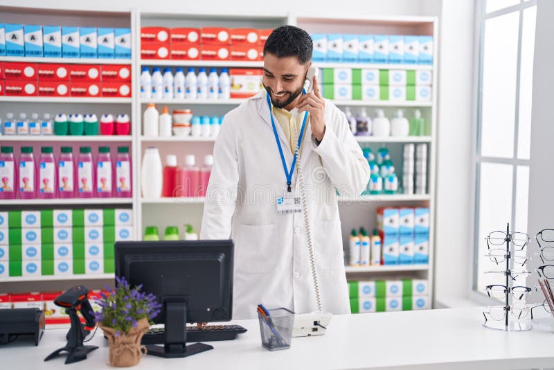 Young Arab Man Pharmacist Talking on Telephone Using Computer at ...