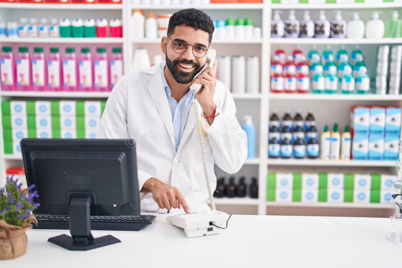 Young Arab Man Pharmacist Talking on Telephone Using Computer at ...